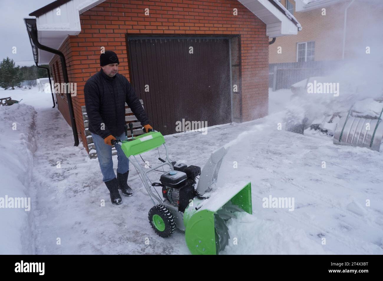 A man cleans snow in the winter in the courtyard of the house, man ...