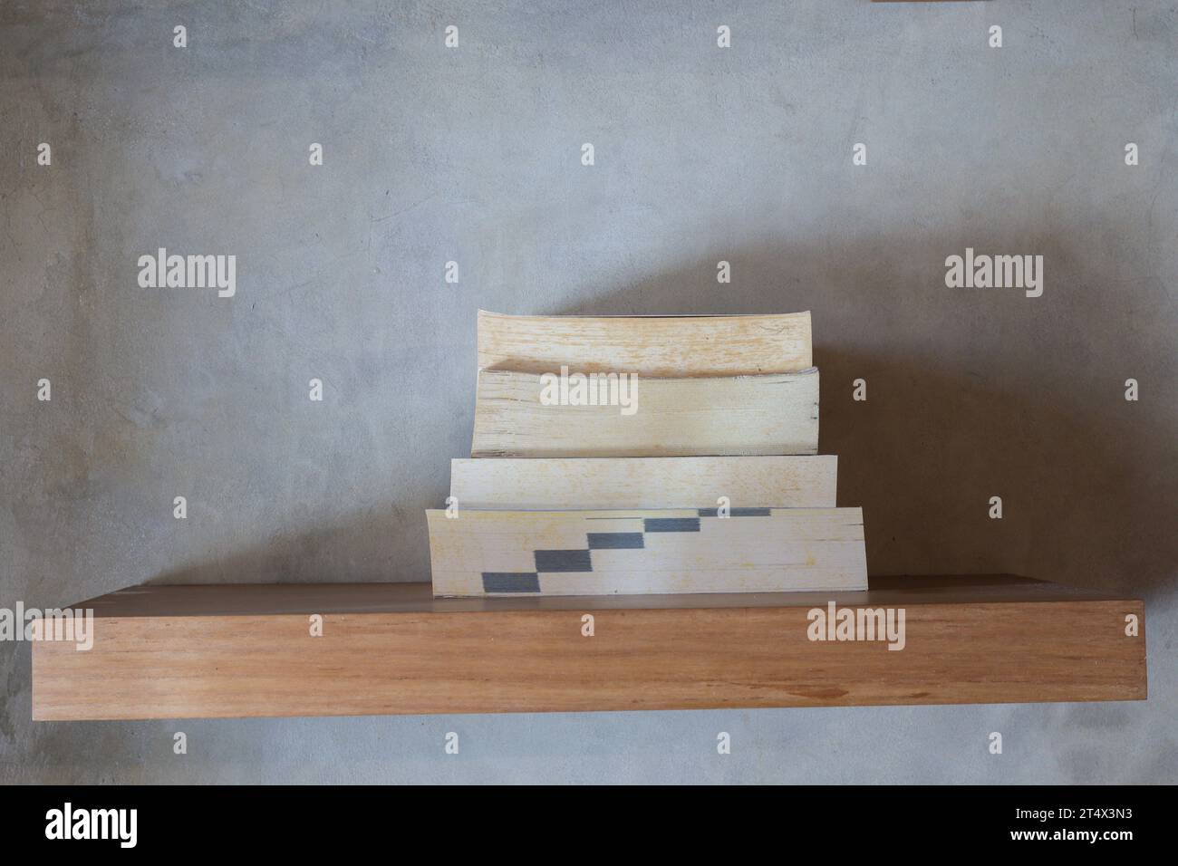 Stack of yellowish and vintage books on floating wooden bookshelf ...