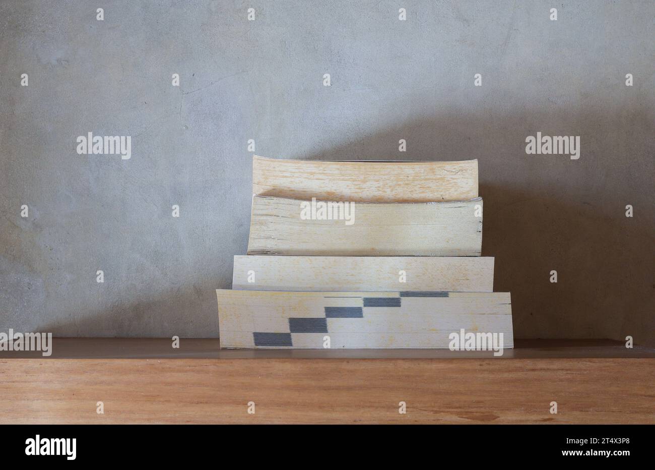 Stack of yellowish and vintage books on floating wooden bookshelf ...