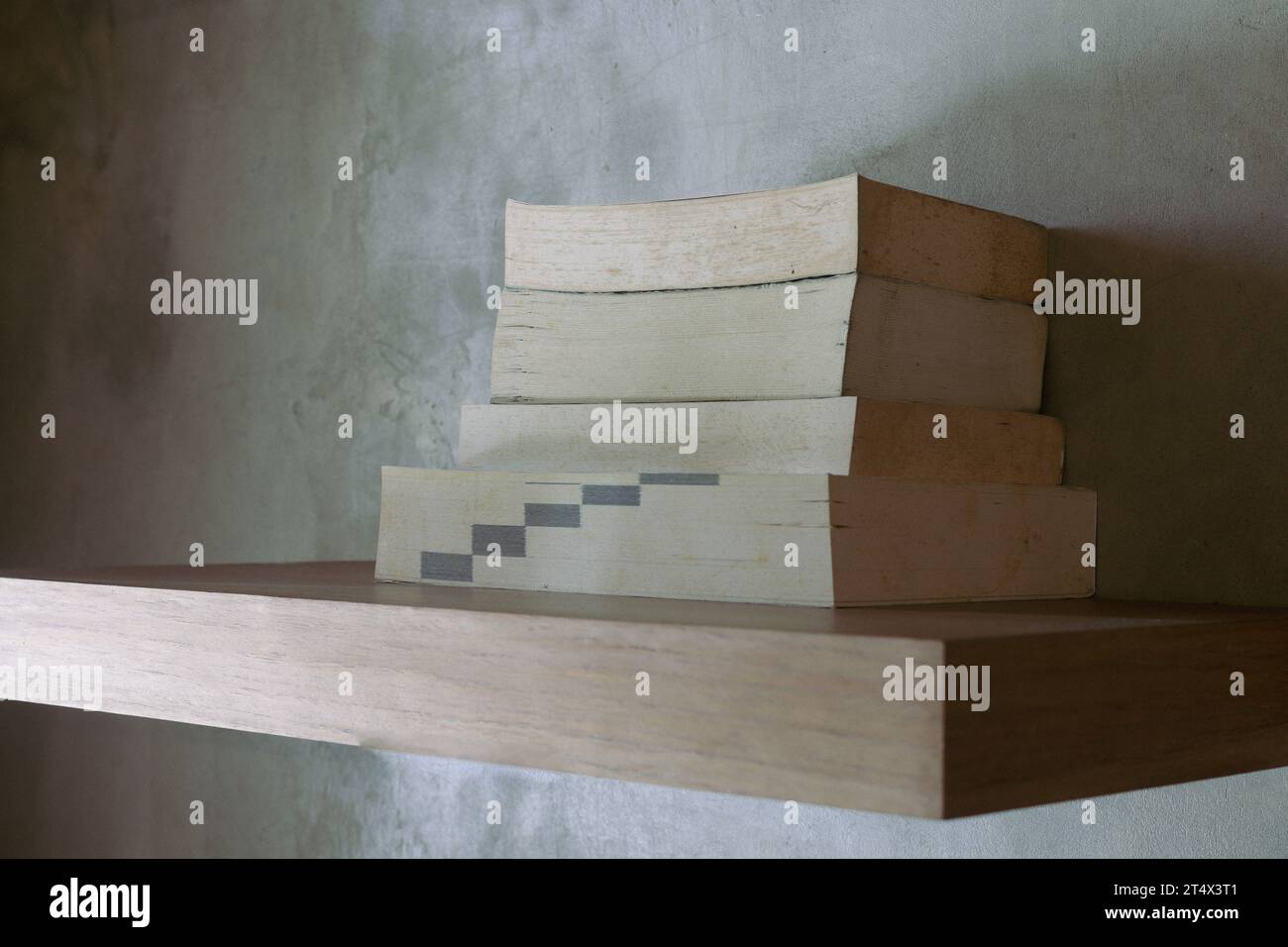 Stack of yellowish and vintage books on floating wooden bookshelf ...