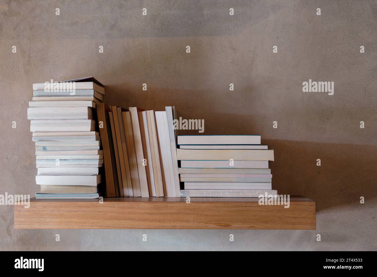 Stack of books on floating wooden bookshelf. Education and knowledge ...