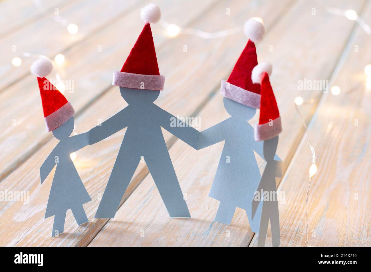 Family of paper people holding hands in Santa Claus hats, family ...