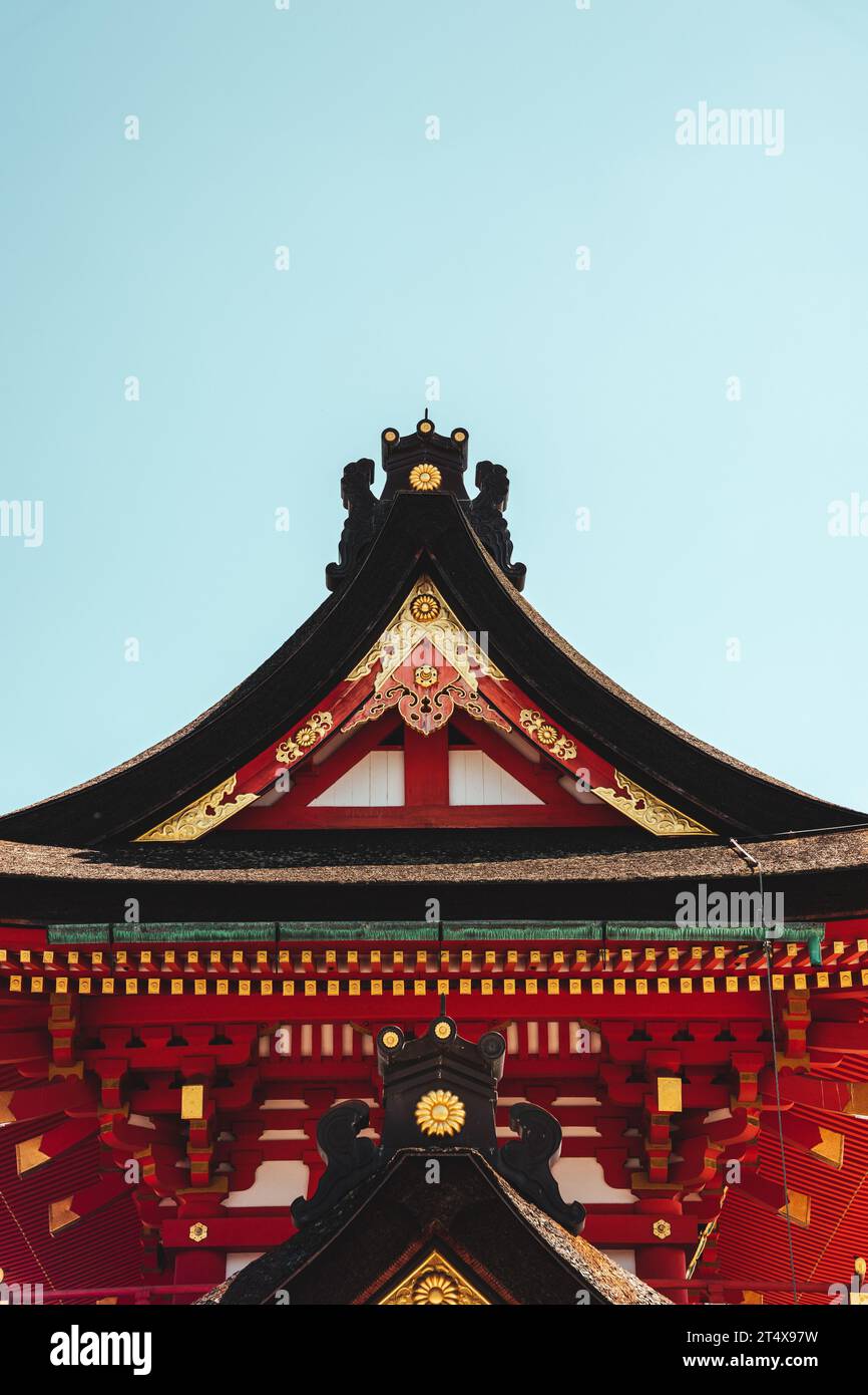 An ornately detailed red Chinese building stands against a bright blue ...