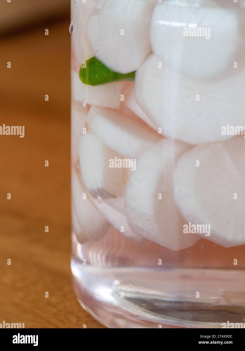 White pickled Daikon Radish discs or slices, clear liquid in a glass ...
