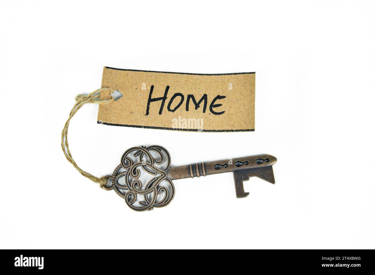 Old decorative key and handwritten tag "HOME" tied with straw rope on ...