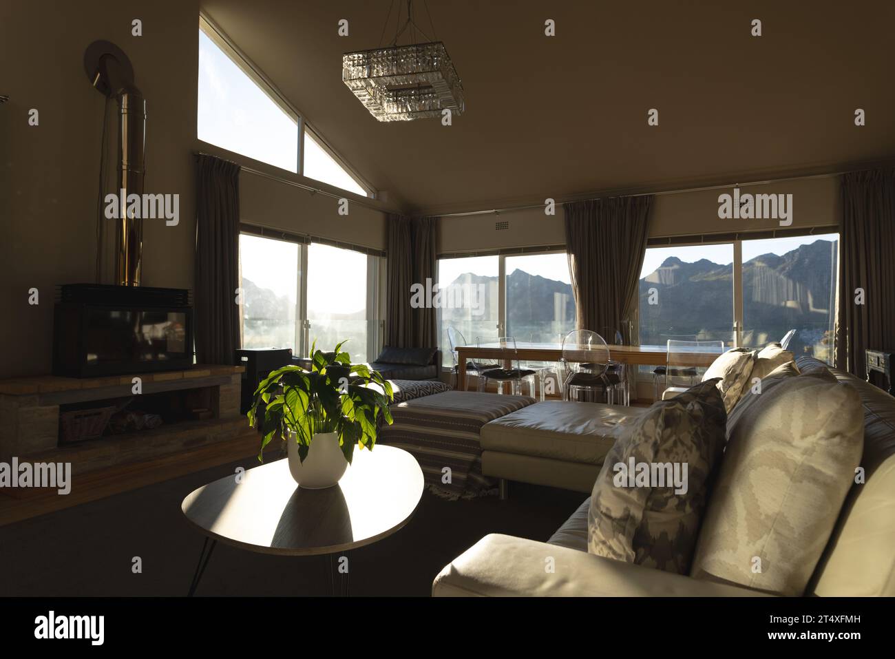 Interior of sunny open plan lounge and dining areas with mountain views ...