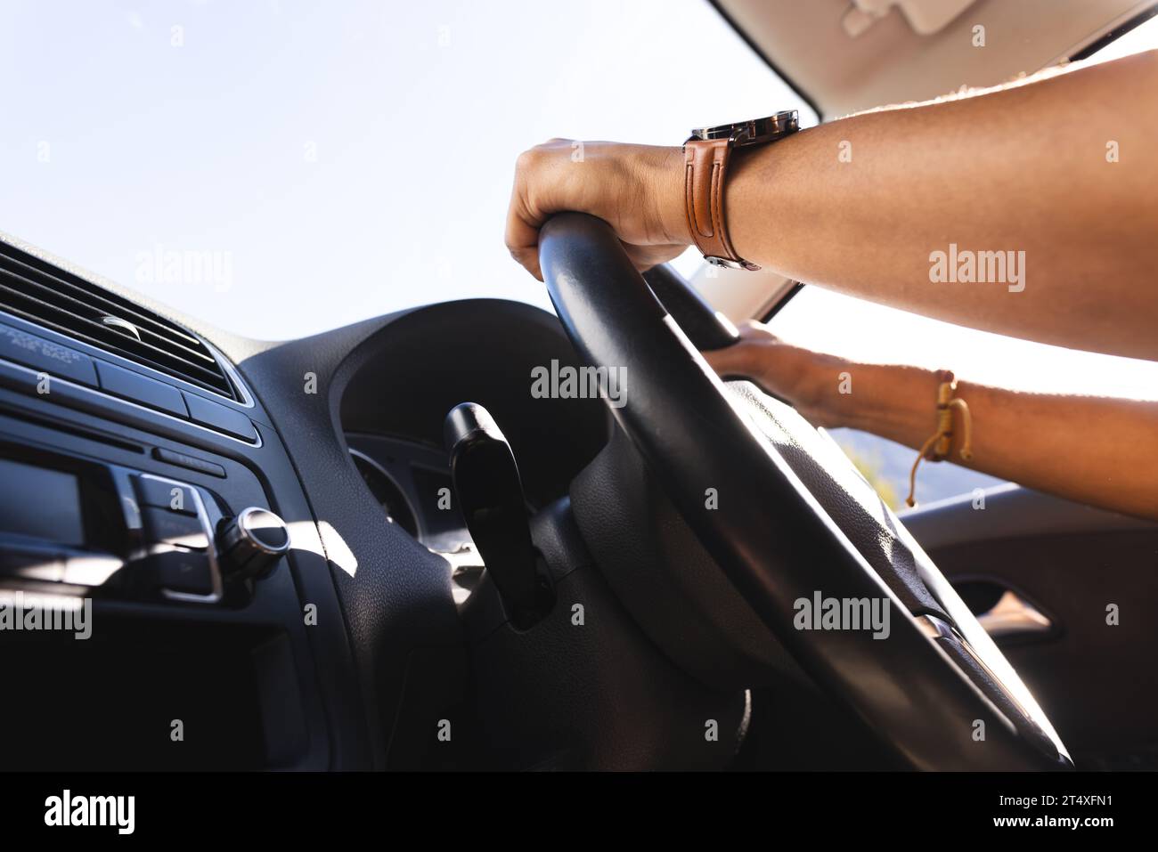 Hands of african american man on steering wheel, driving car on sunny ...