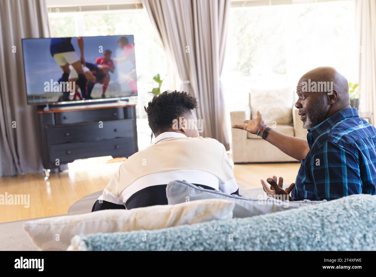 Happy African American Father And Adult Son Watching Sports On Tv And