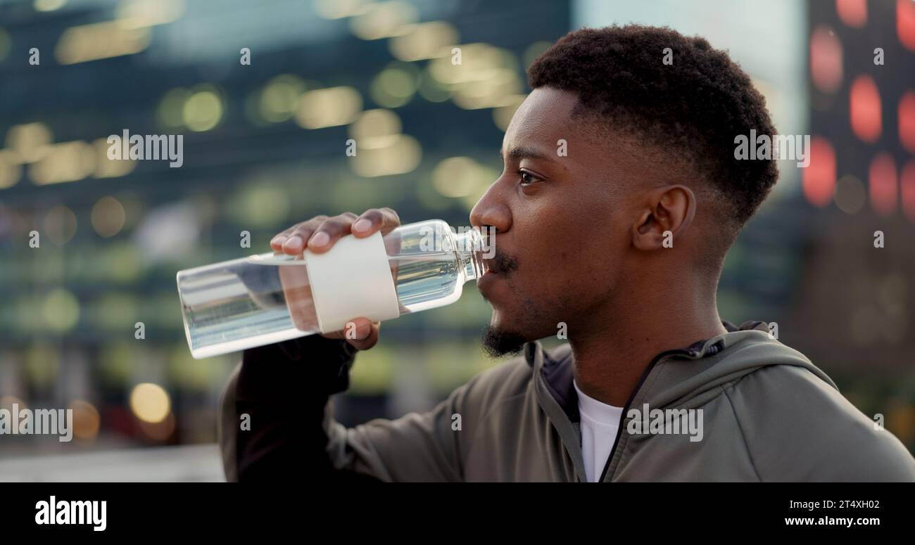 Black man, drinking water and fitness in city after workout, exercise ...