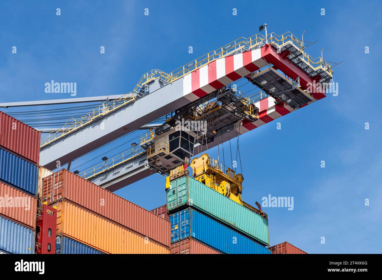 Low angle view of section of stacked sea containers being handled by a ...