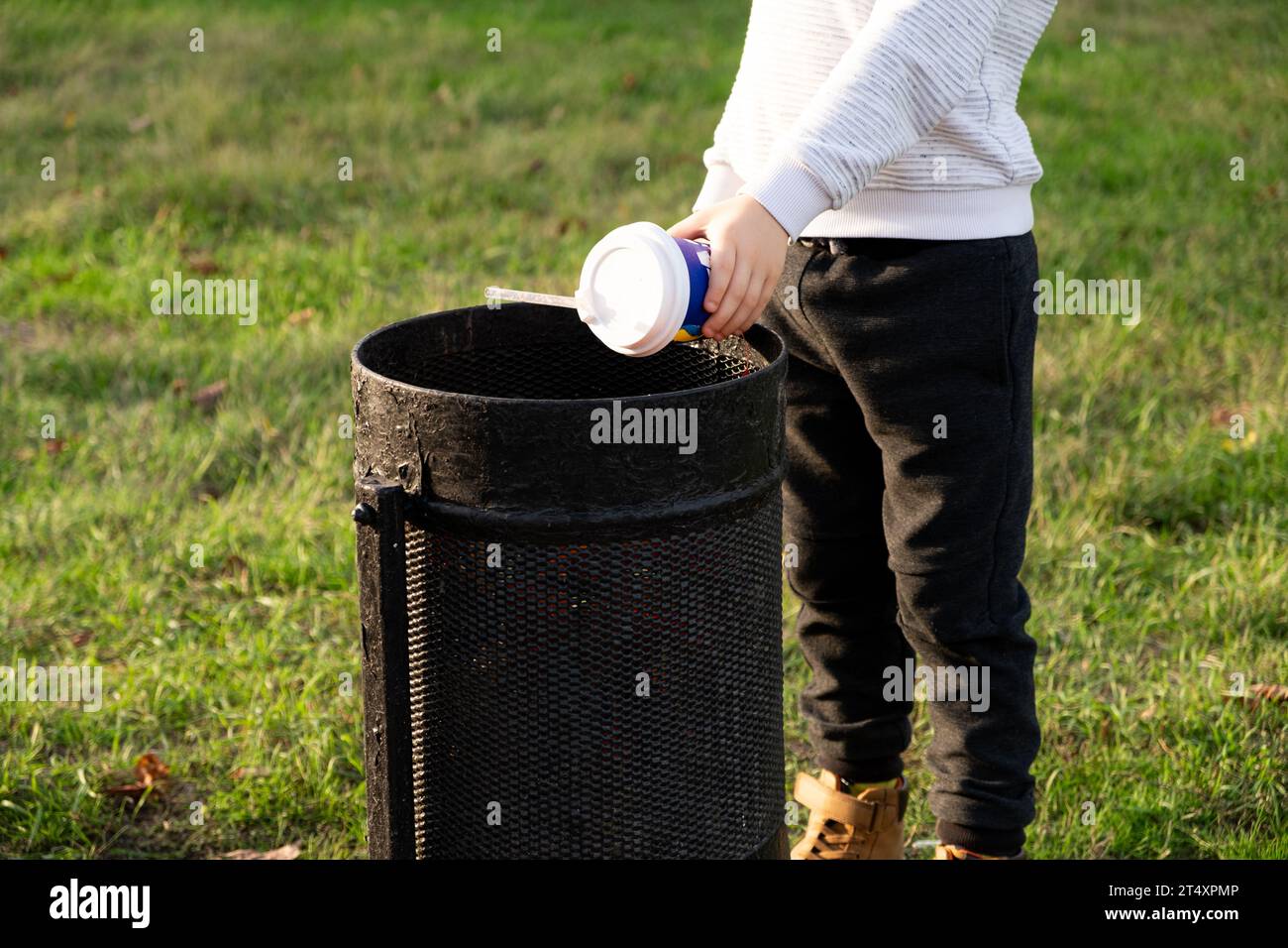 A child throws a plastic cup in the trash. Garbage recycling and ...