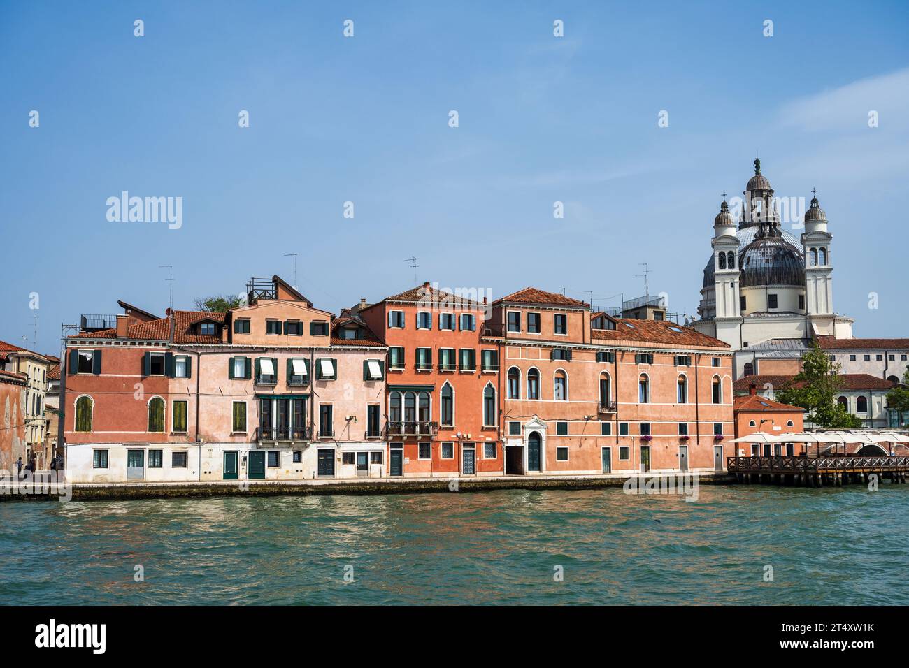 Colourful buildings on the Zattere promenade, with bell towers and dome ...