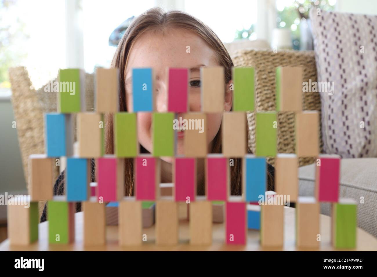 Teenage girl looking through a wall of wooden blocks with gaps Stock ...