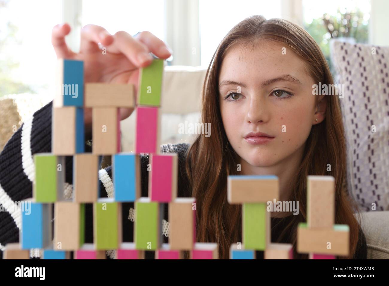 Teenage girl constructing a wall of wooden blocks and building a tower ...