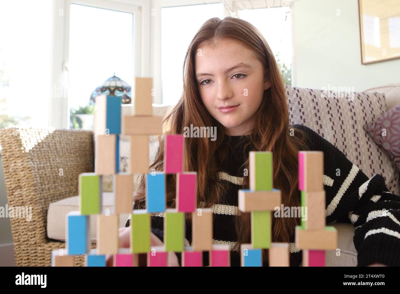 Teenage girl constructing a wall of wooden blocks and building a tower ...