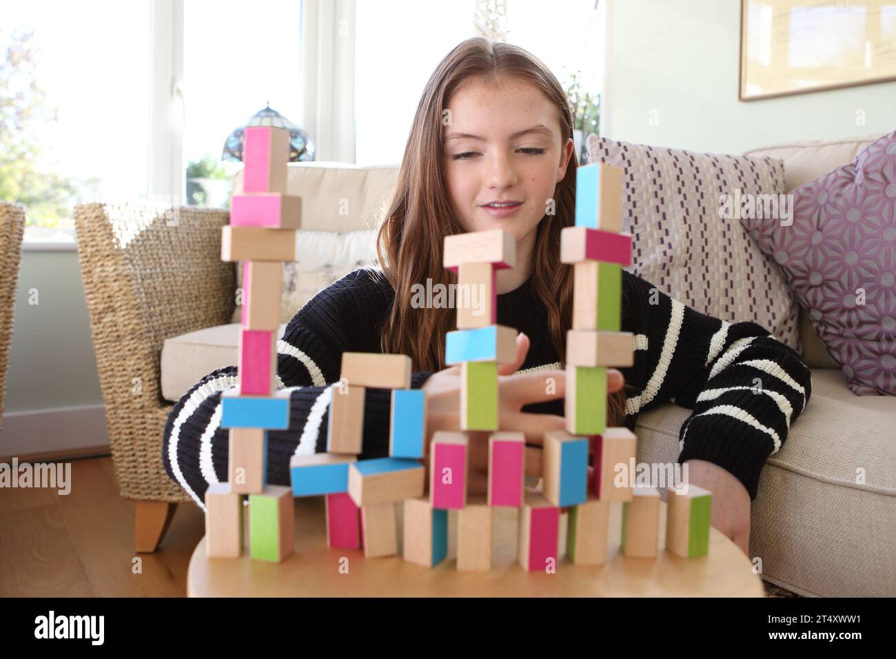 Girl smiling and laughing destroying a wall and towers of wooden blocks ...