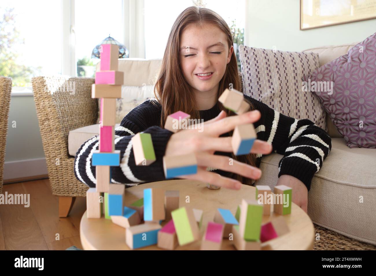 Teenage girl smiling and laughing destroying a wall and towers of ...