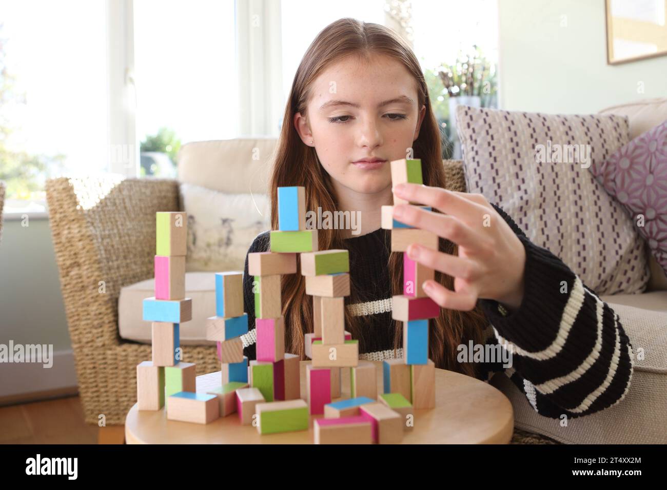 Teenage girl constructing a wall of wooden blocks and building a tower ...
