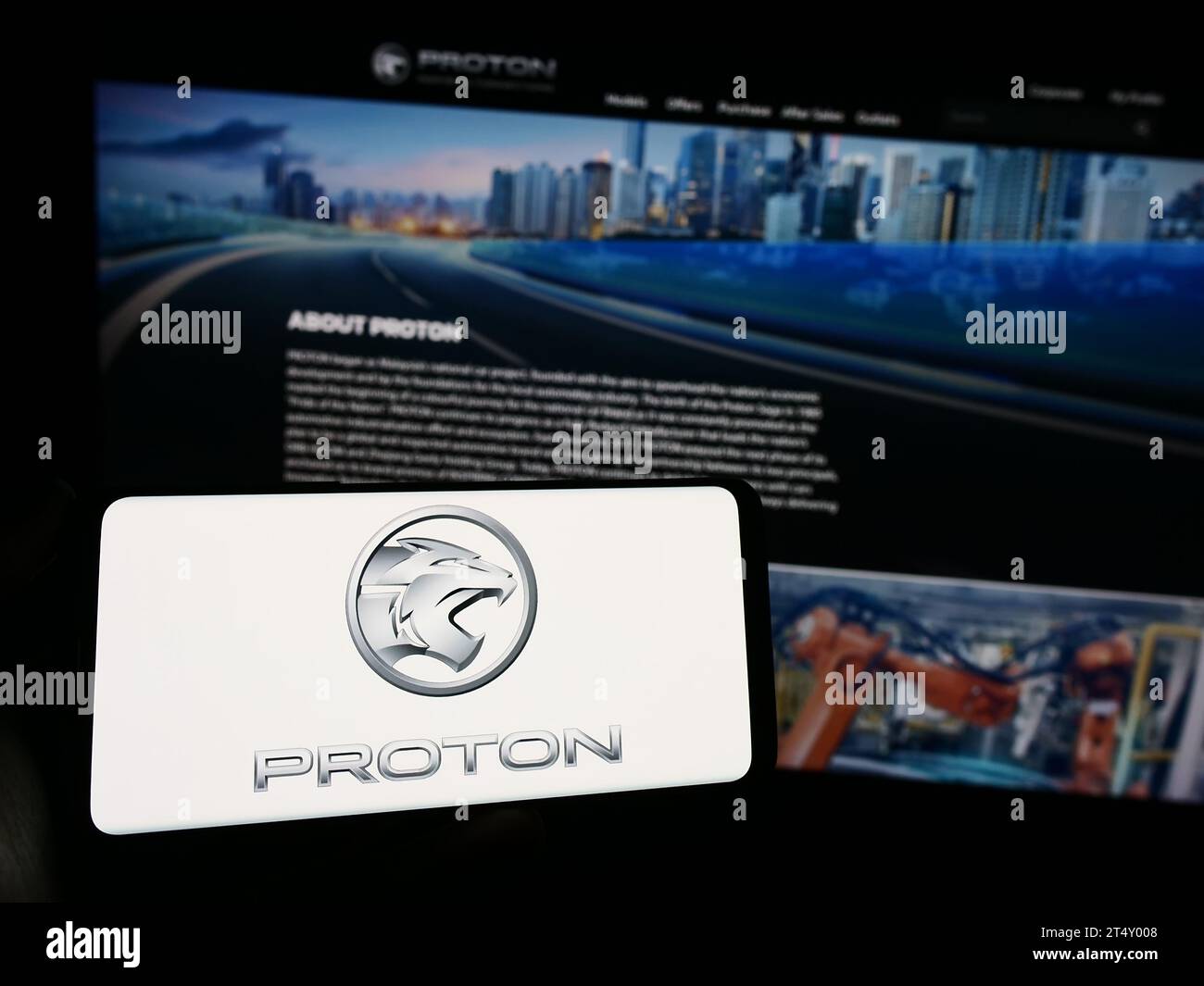 Person holding mobile phone with logo of Malaysian automotive company ...