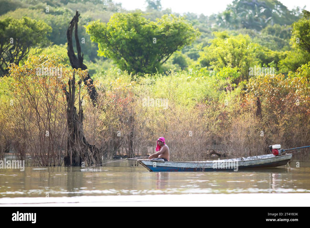 Brazilian man sitting in a boat fishing in the Rio Amazonas, Manaus ...