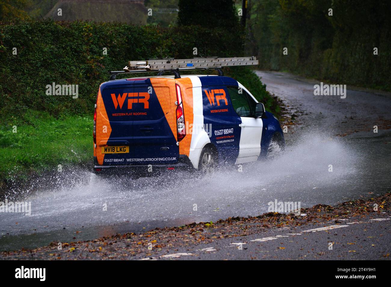 A van driving through rainwater running off a field in Exeter as Storm ...