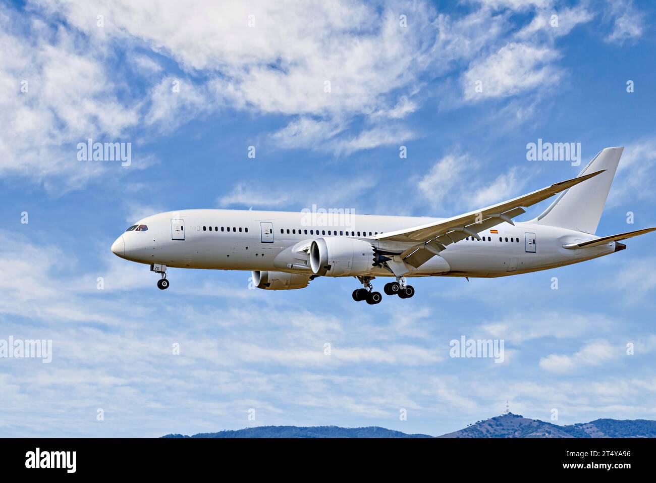 Boeing 787-8 Dreamliner passenger plane landing at the airport, under a blue sky with white ...