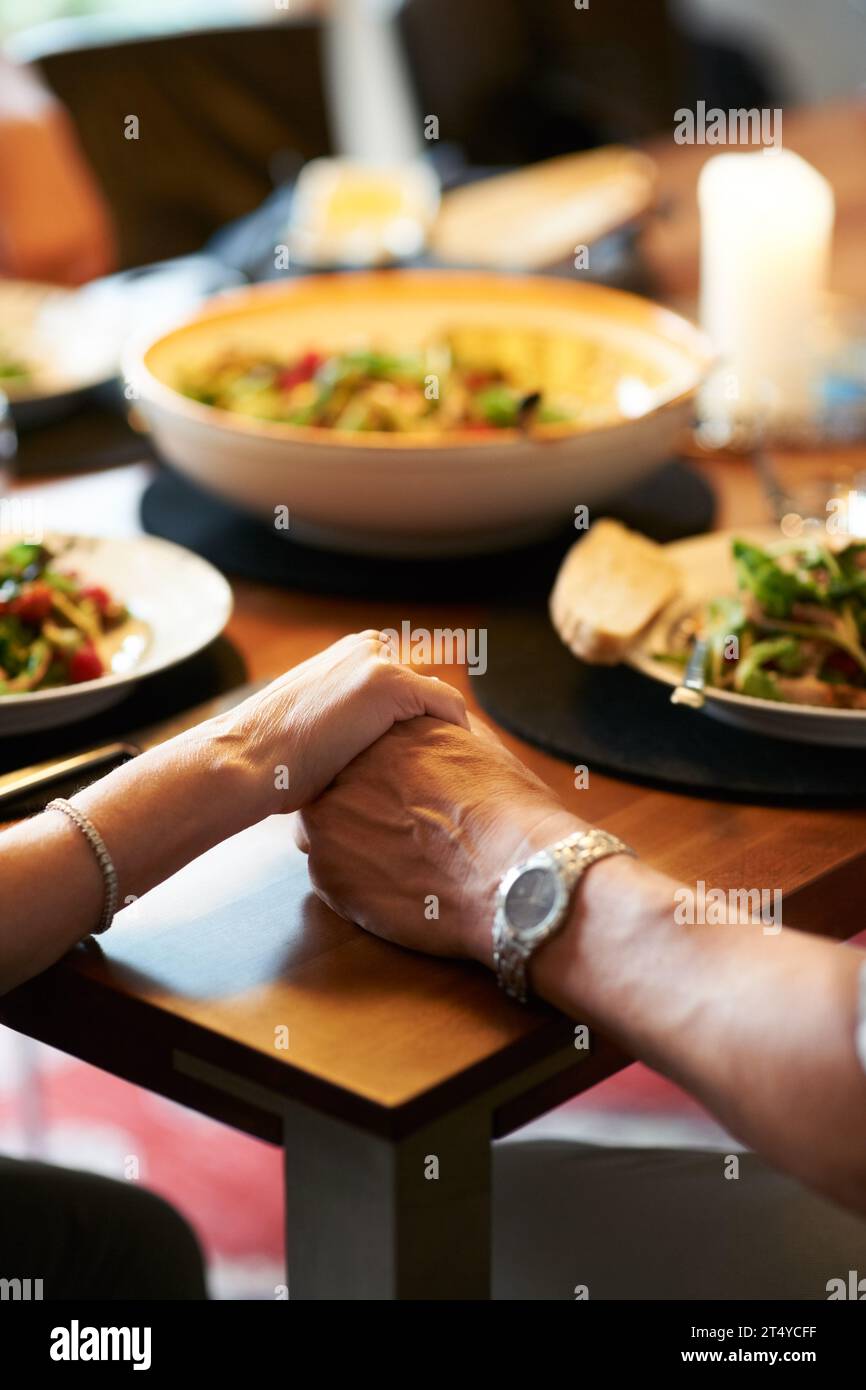 Holding hands, home or couple praying for food or support at a dinner ...