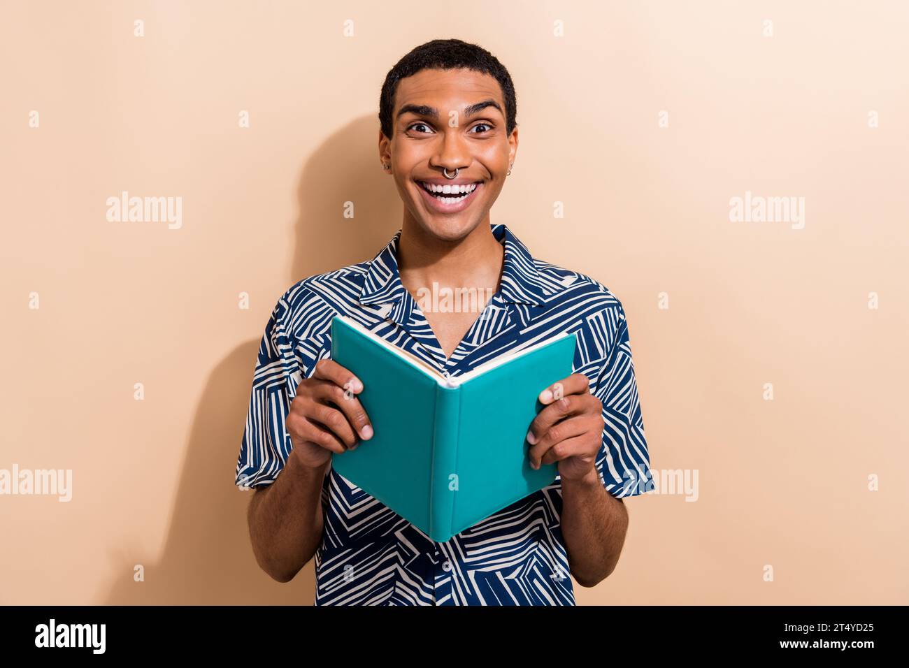Photo of cheerful excited guy wear print shirt reading interesting book ...