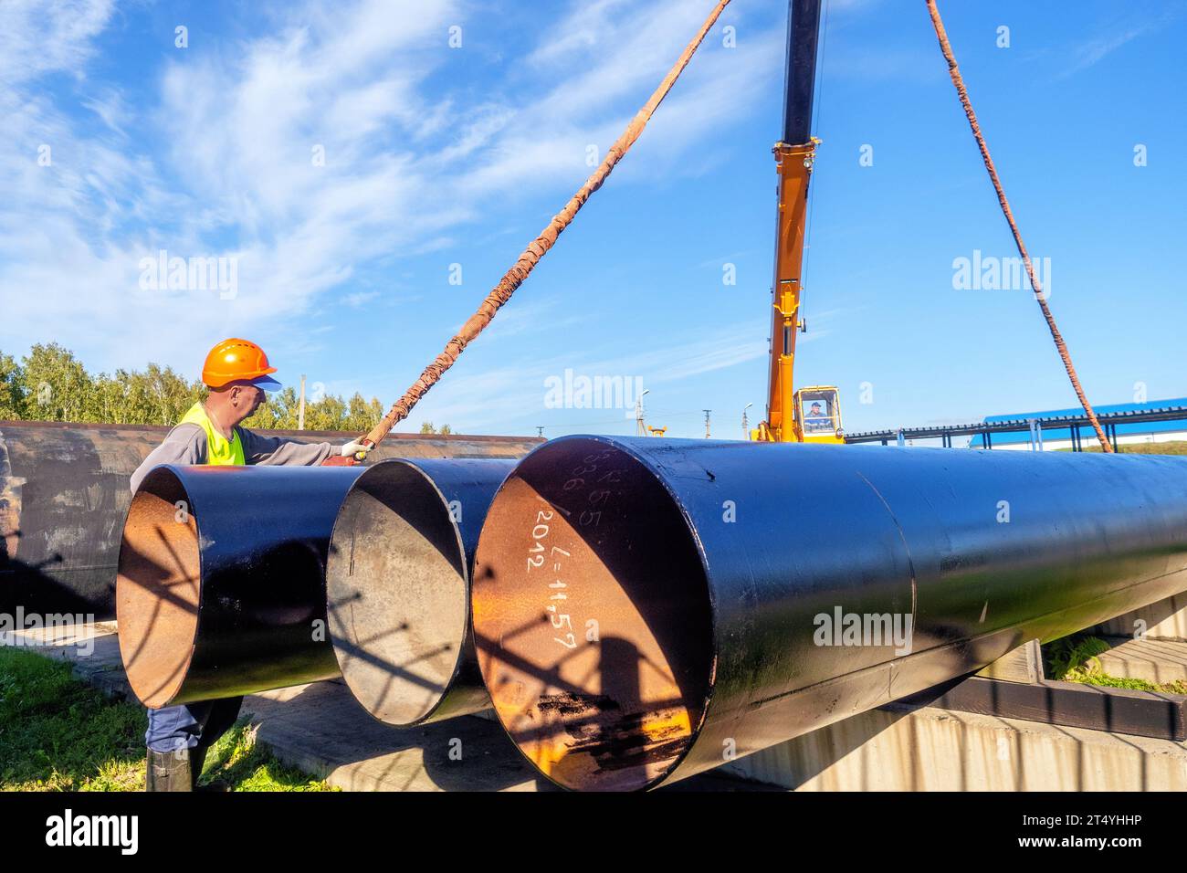 Slinger unloads large gasification pipes on summer day. Pipes for ...