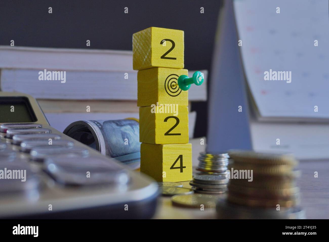 Wooden cube with number 2024 and pushpin surrounded by money and ...
