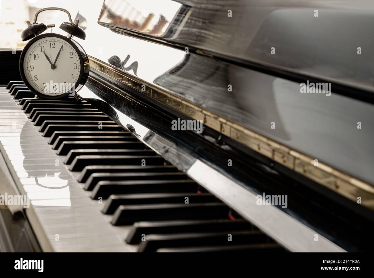 Black alarm clock stand on the Piano Keyboard. Time for music concept ...