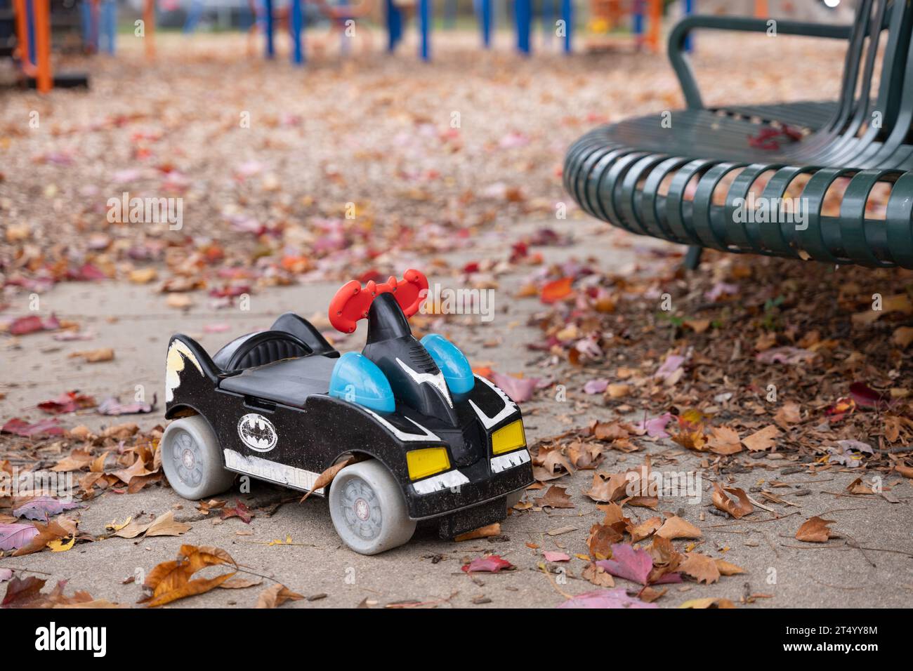 Toy Batmobile ride on car in a park in autumn, with leaves on the ...