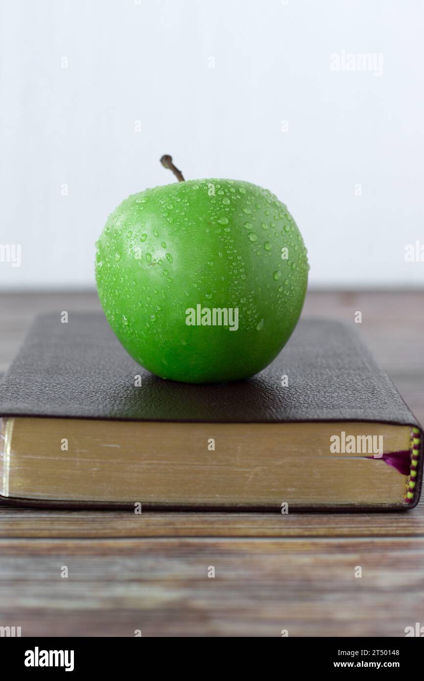 Green apple on Holy Bible Book on wooden table with white background ...