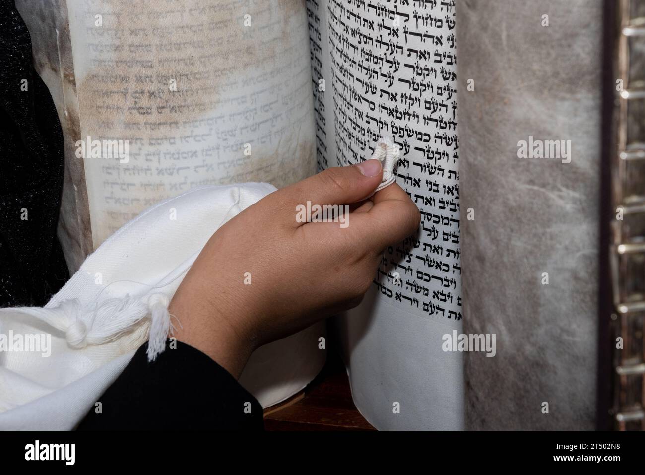 A reader uses the strings of his prayer shawl to guide his eyes across ...