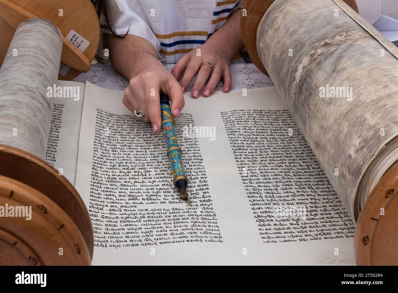 A reader uses a pointer to guide his eyes across the text of a Torah ...