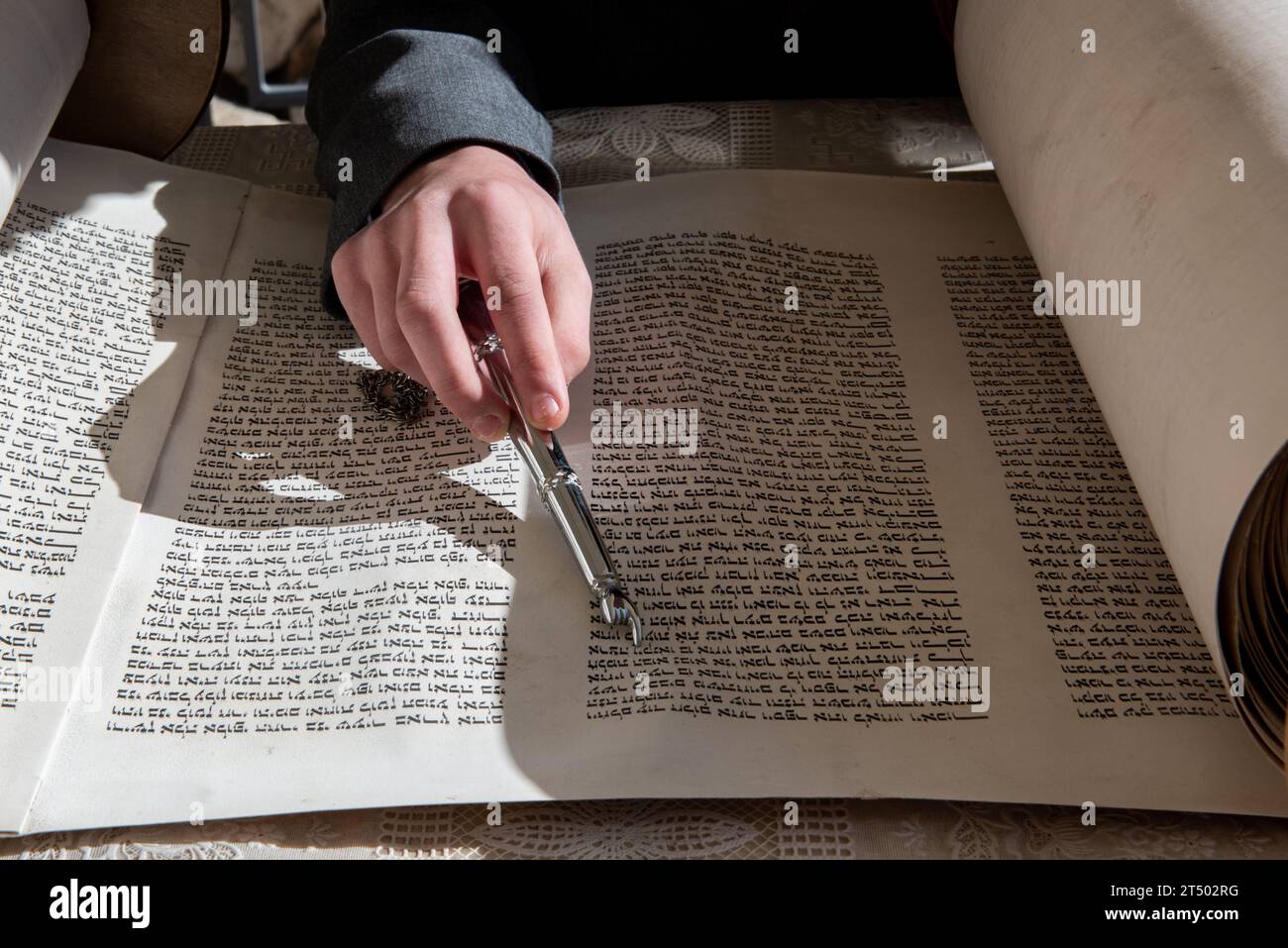 A reader uses a pointer to guide his eyes across the text of a Torah ...