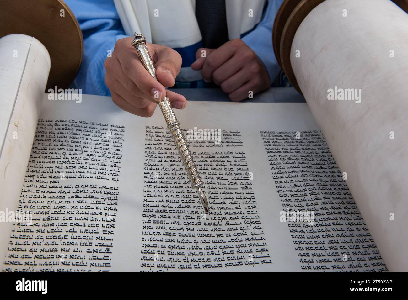 A reader uses a pointer to guide his eyes across the text of a Torah ...