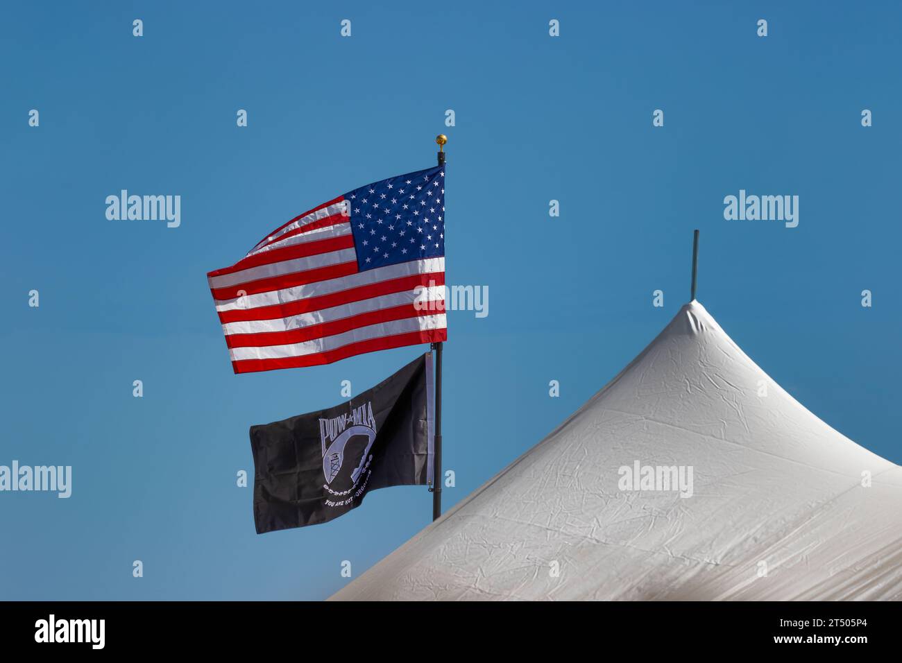 Under blue skies the American Flag and POW Missing in action flags fly ...