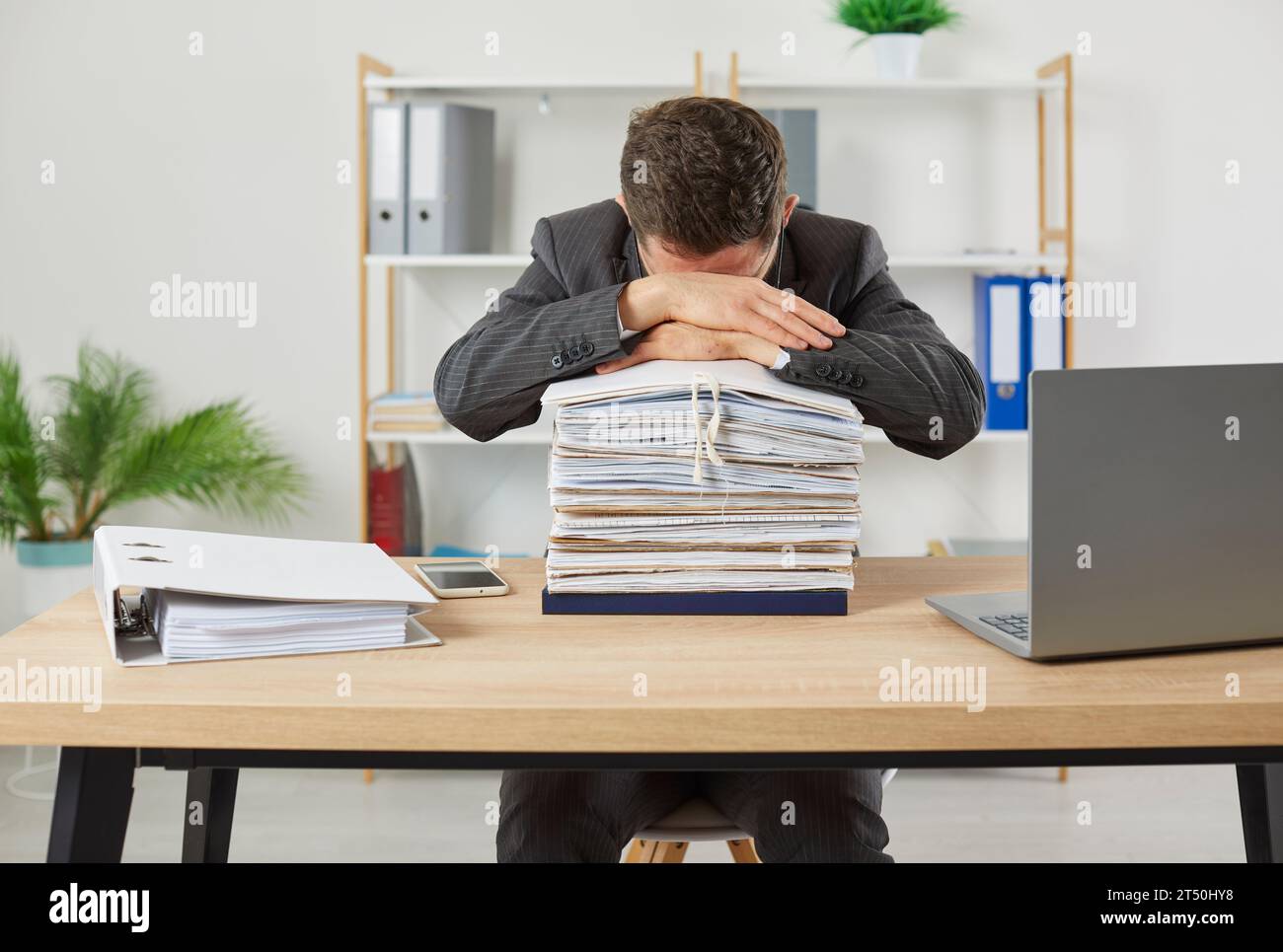 Tired male office worker dozing off leaning on stack of folders with ...