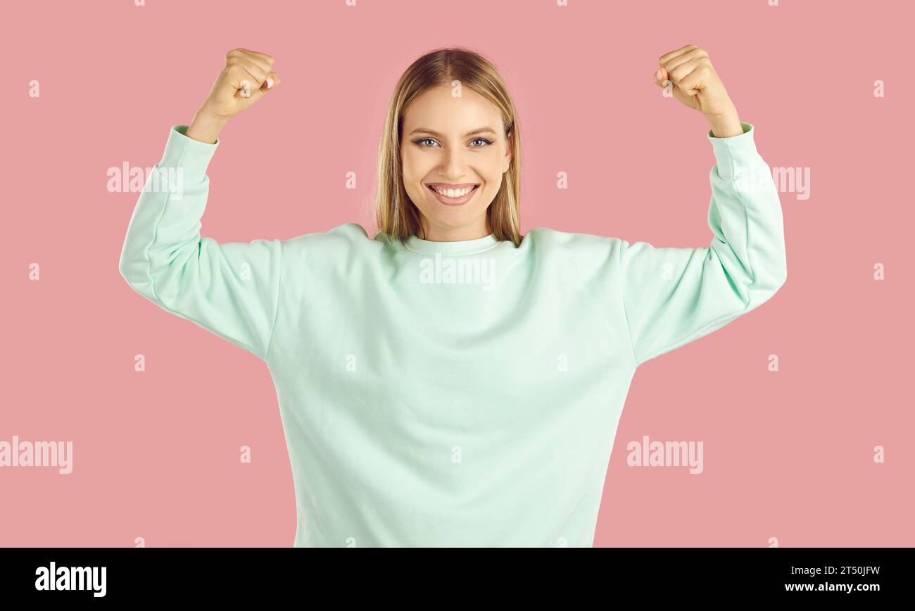 Beautiful confident and strong woman jokingly raises her arms up and ...