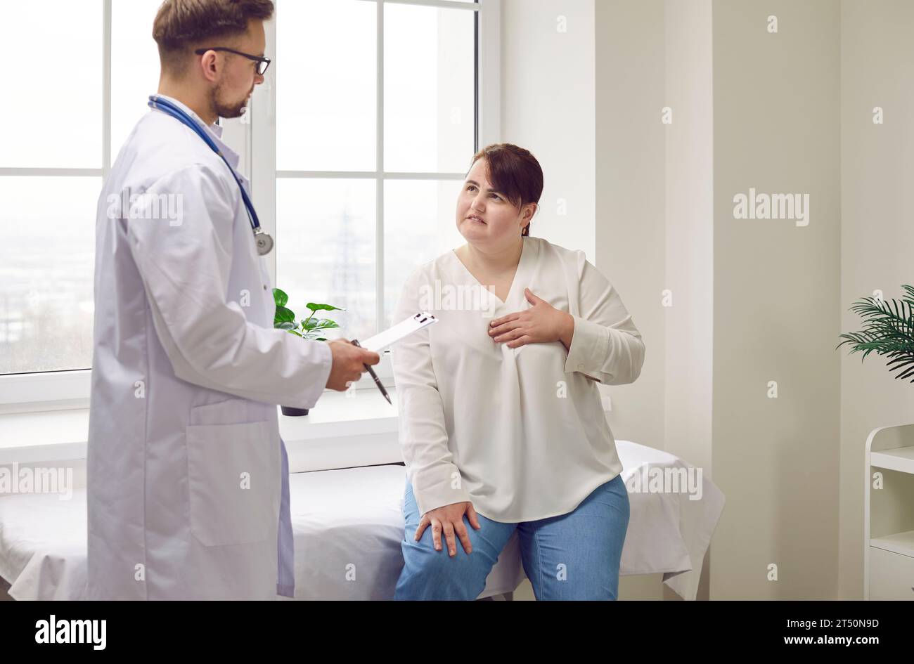 Fat woman sitting in the doctor's office pointing to her chest during ...