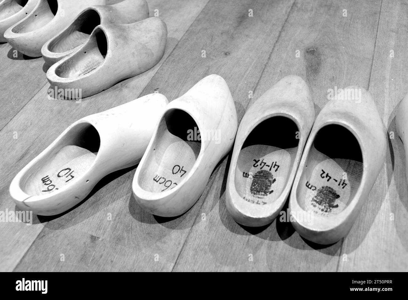 A line of traditional Dutch wooden clogs arranged on the floor, in ...