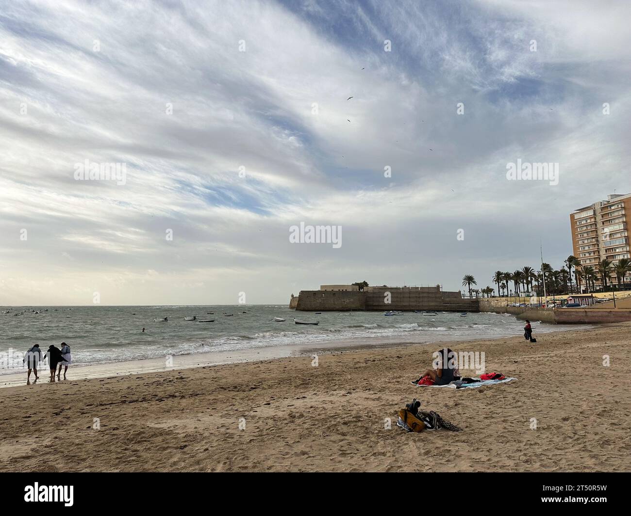 02 November 2023, Spain, Cádiz: People sitting on La Caleta beach in ...