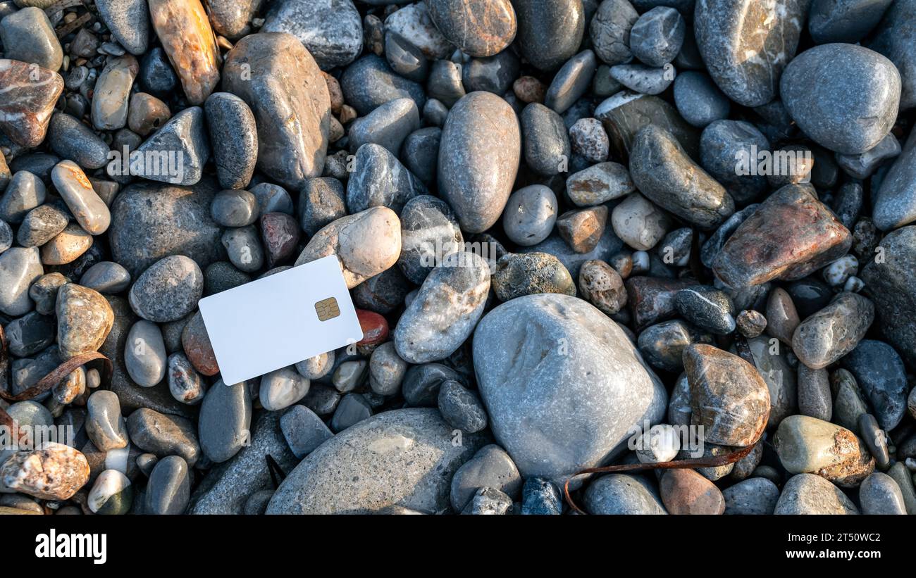White bank card laid on gray smooth stones. Money and nature concept ...