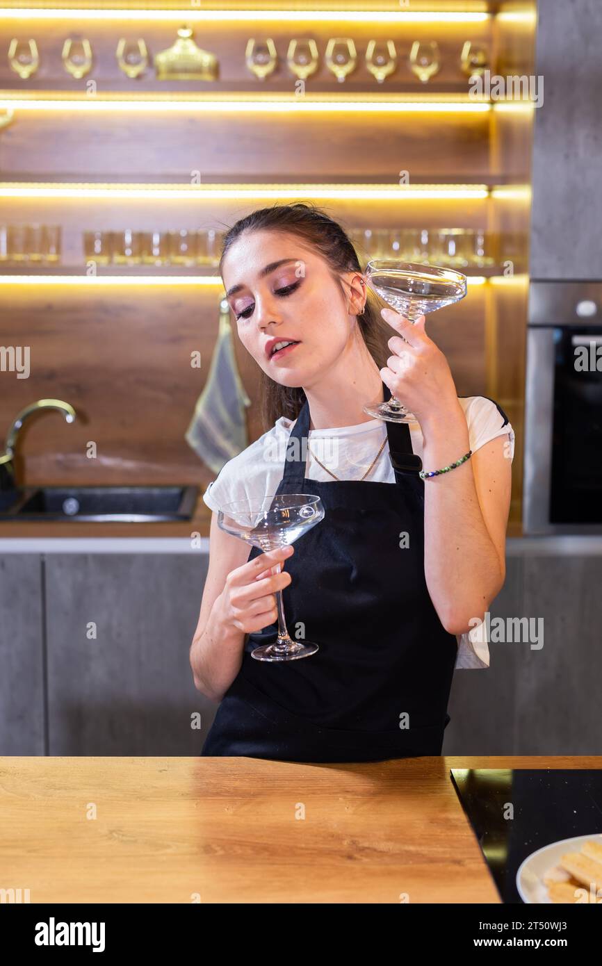 Female chef in uniform holding glasses for wine while smiling and ...