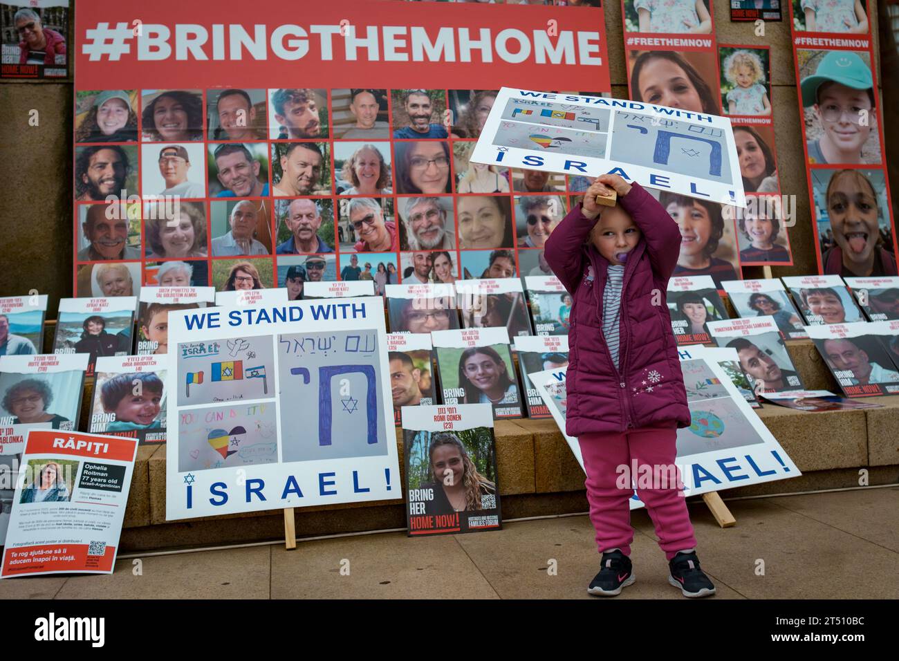 A child holds a banner backdropped by photographs of Israelis kidnapped ...