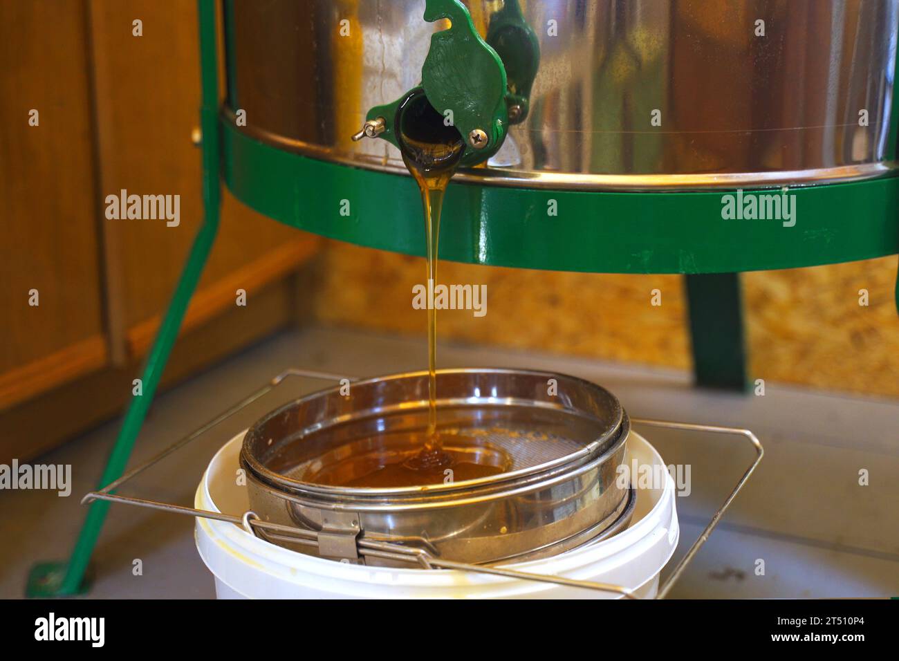 Honey production. The beekeeper opens the honey extractor valve and the ...