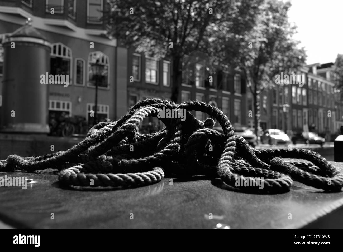 An urban street scene with a rope lying on the edge of the pavement in ...