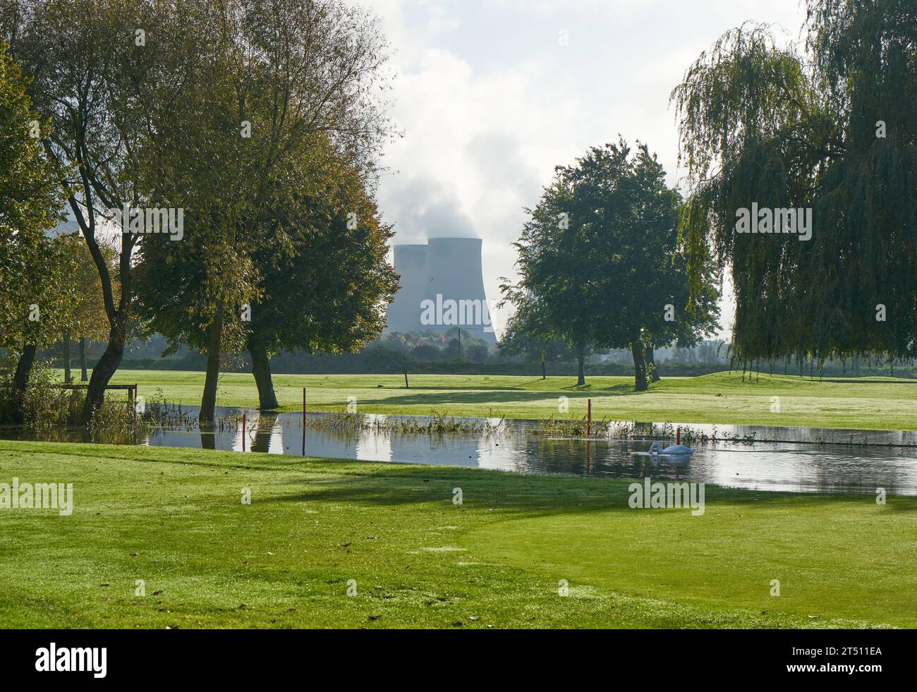 Water trap on a golf course with distant power station cooling towers ...