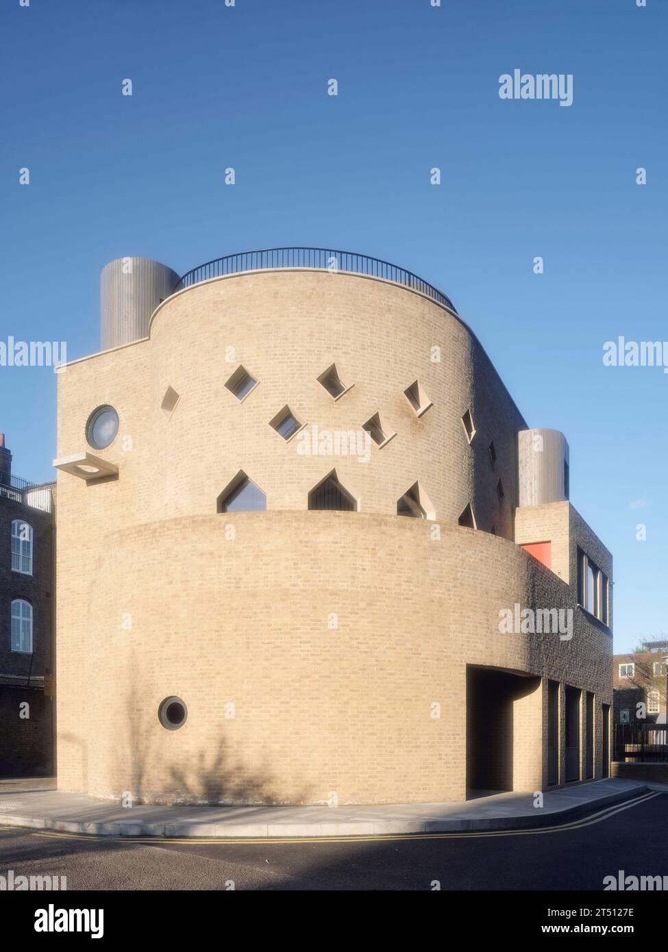 Sunlit brick facade with circular and diamond-shaped windows. The ...